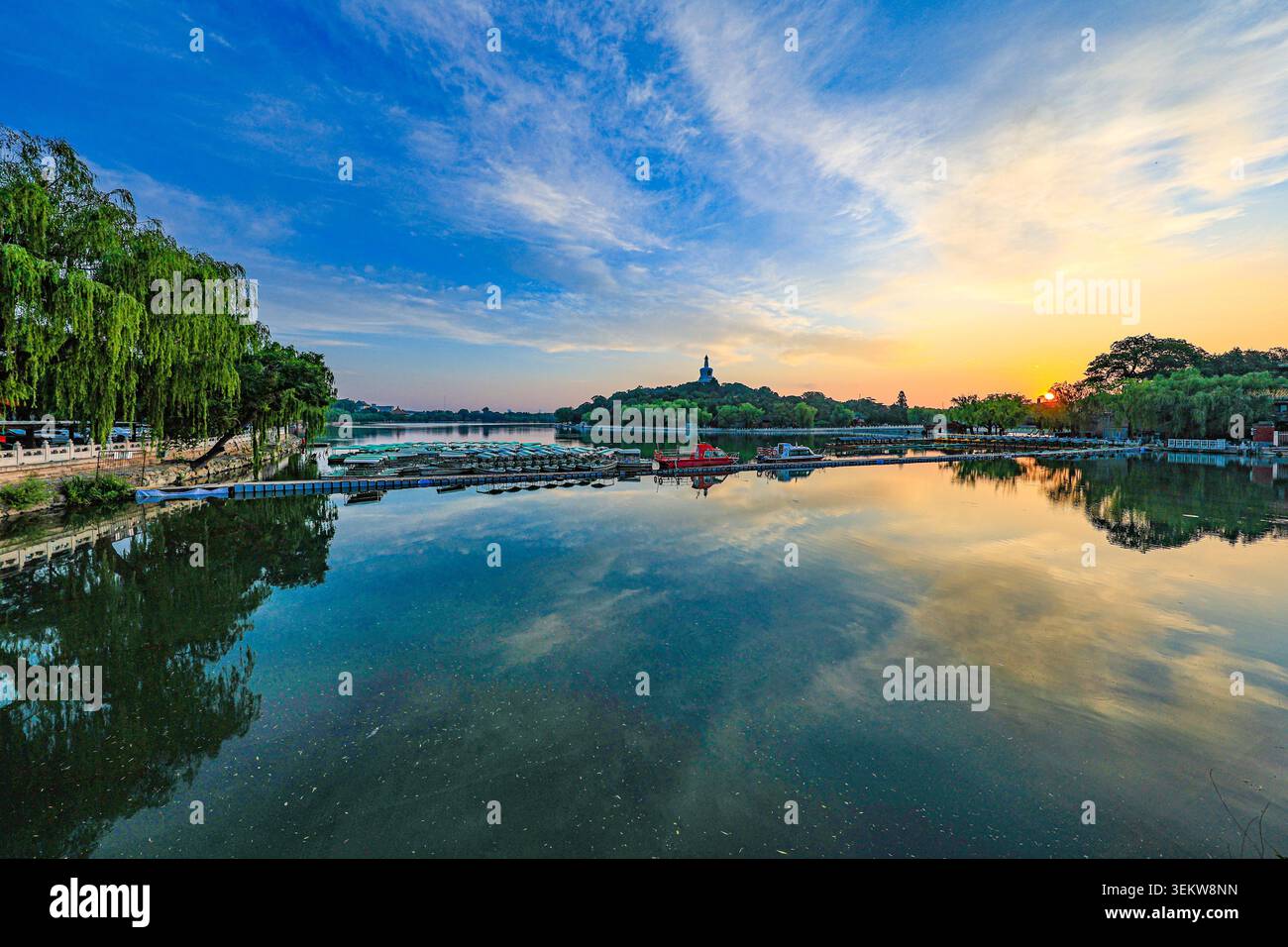 The morning glow tints the lake surface red at Beihai Park in Beijing ...