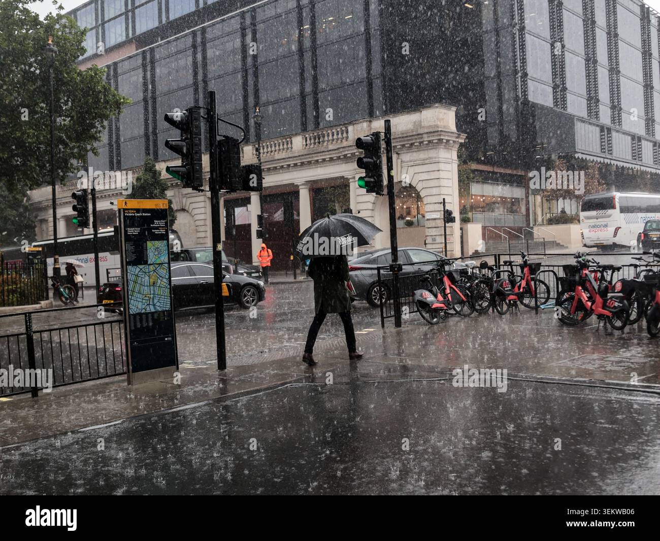 A man seen walking in rain and tander storm disrupted commute. (Photo ...