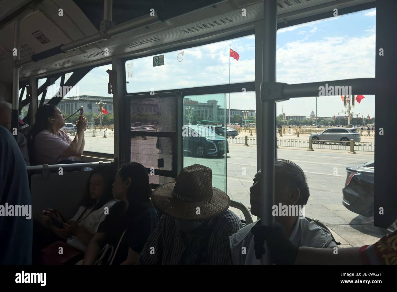 A woman films as commuters ride on the bus traveling past the Tiananmen ...