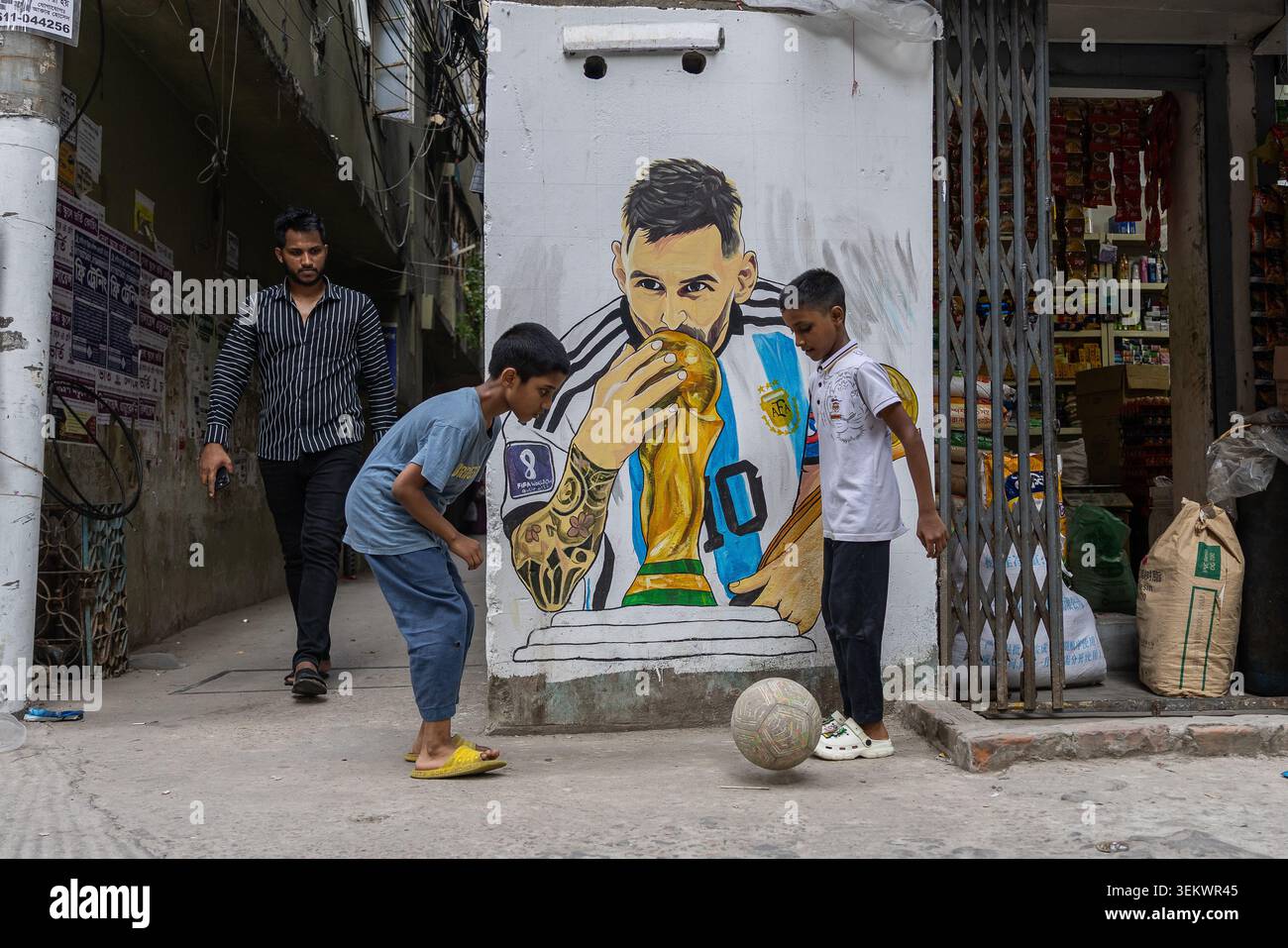 Two boys seen playing foot ball in front of a graffiti of famous ...