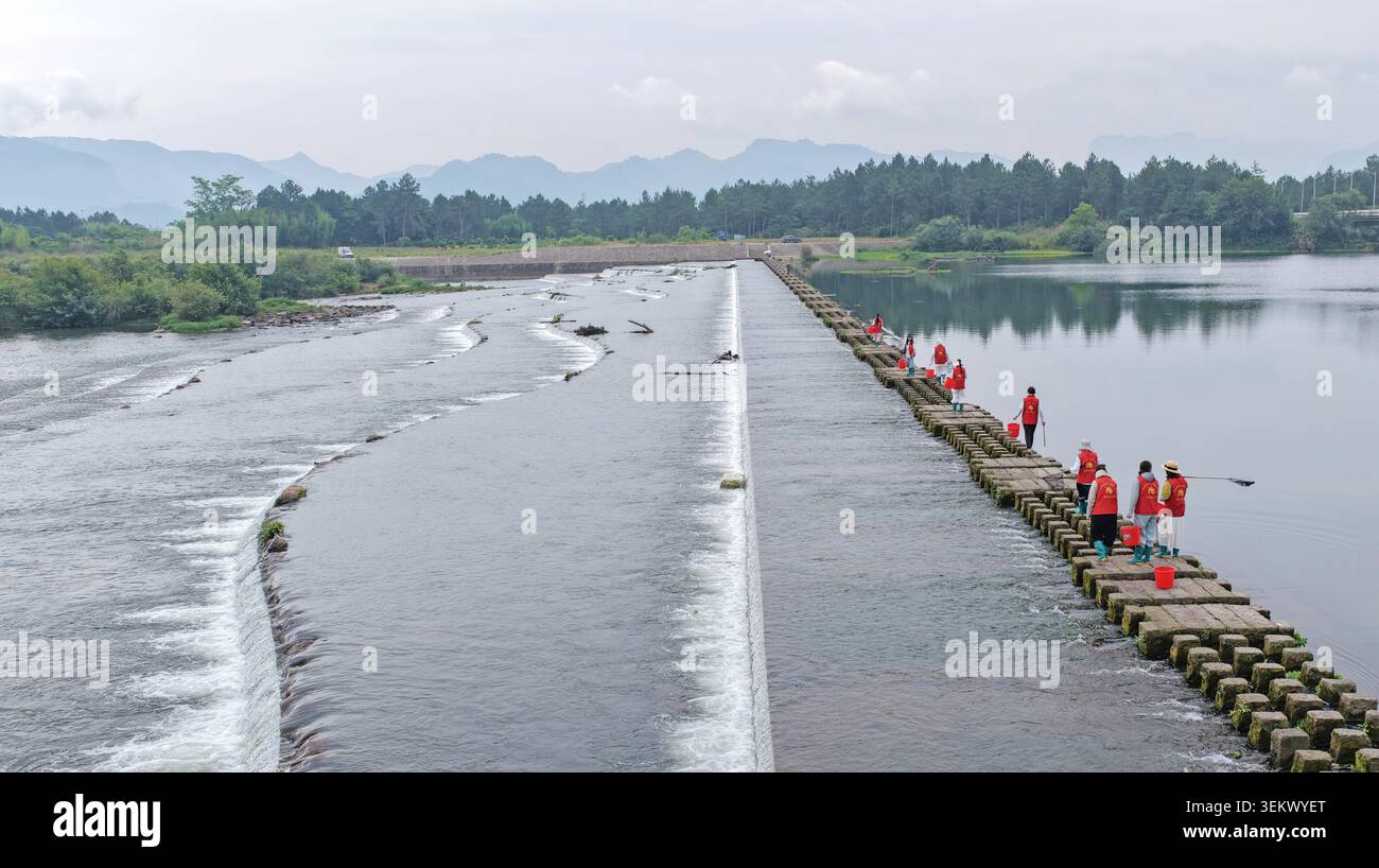 Party members and volunteers clean the Yong'an River in Xiandu County ...