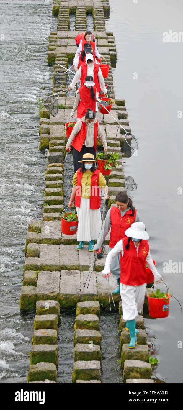 Party members and volunteers clean the Yong'an River in Xiandu County ...