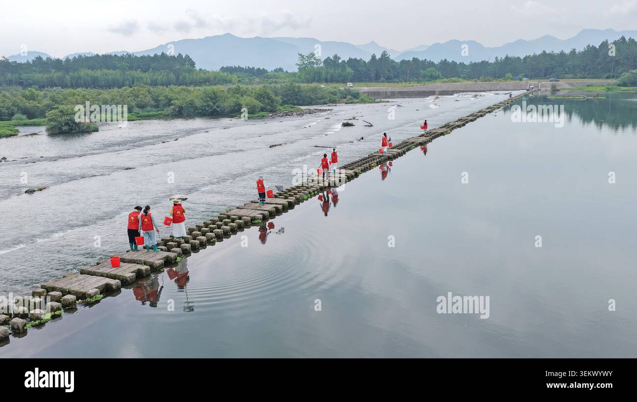Party members and volunteers clean the Yong'an River in Xiandu County ...
