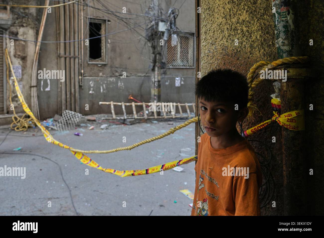 A boy stands in an alley where a restaurant and hotel building caught ...