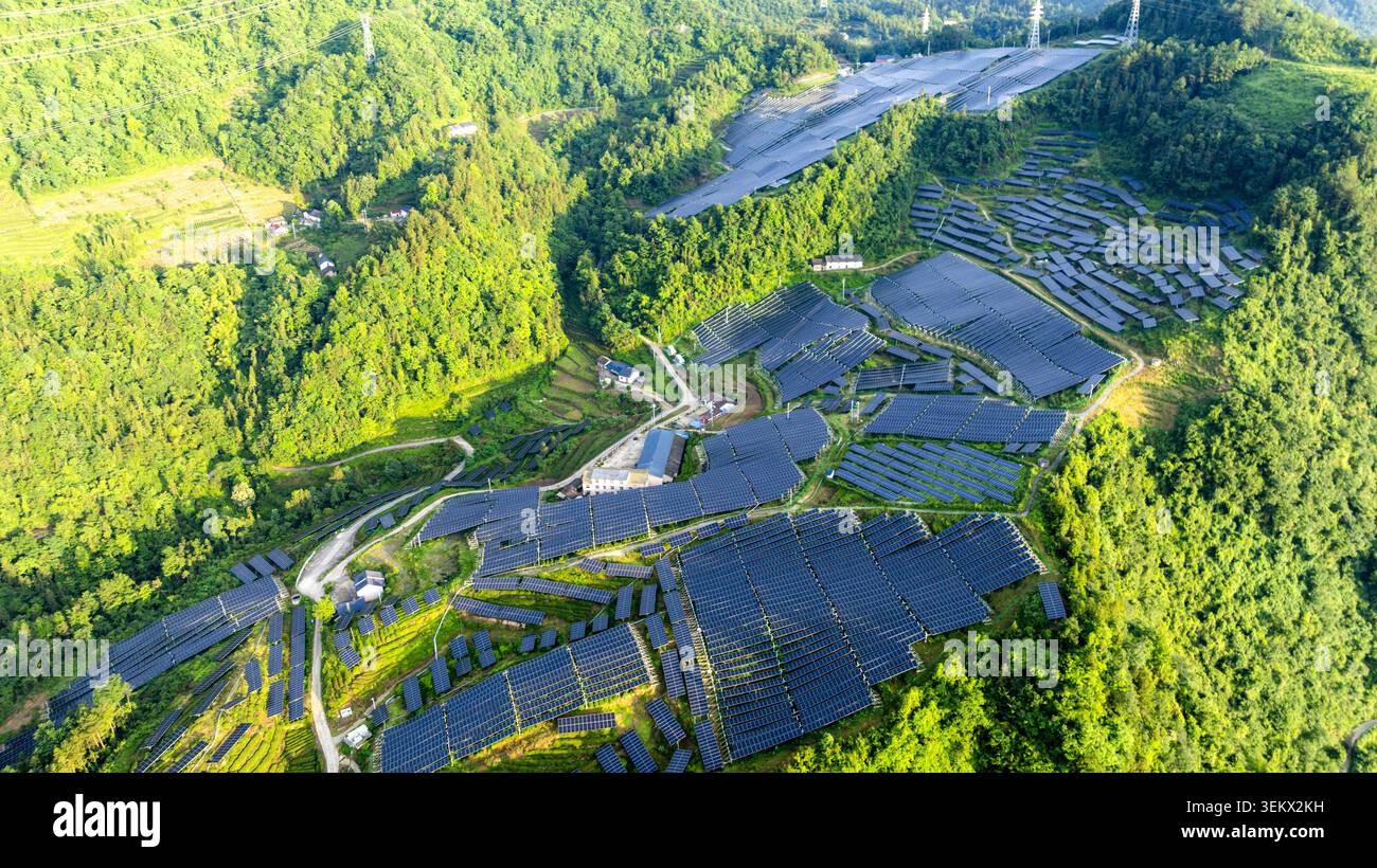 Solar panels stand against green mountains and blue sky at a ...