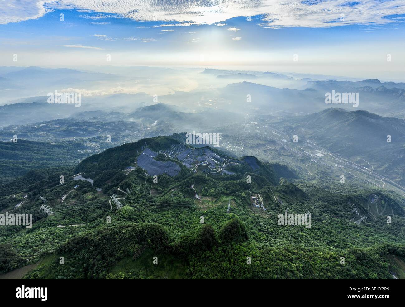 Solar panels stand against green mountains and blue sky at a ...
