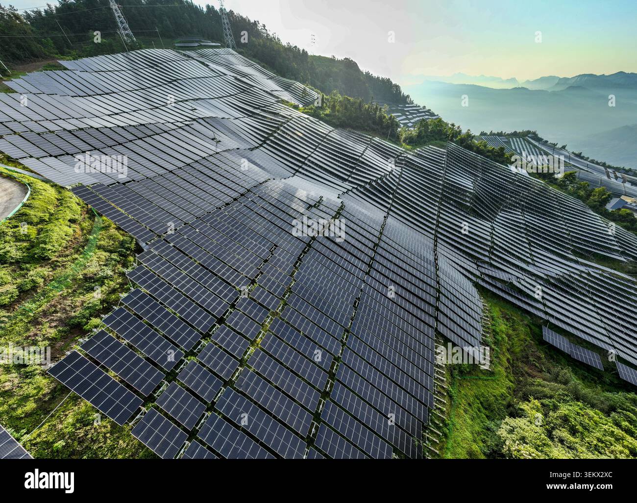Solar panels stand against green mountains and blue sky at a ...