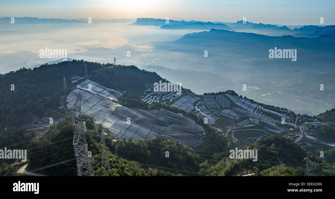 Solar panels stand against green mountains and blue sky at a ...
