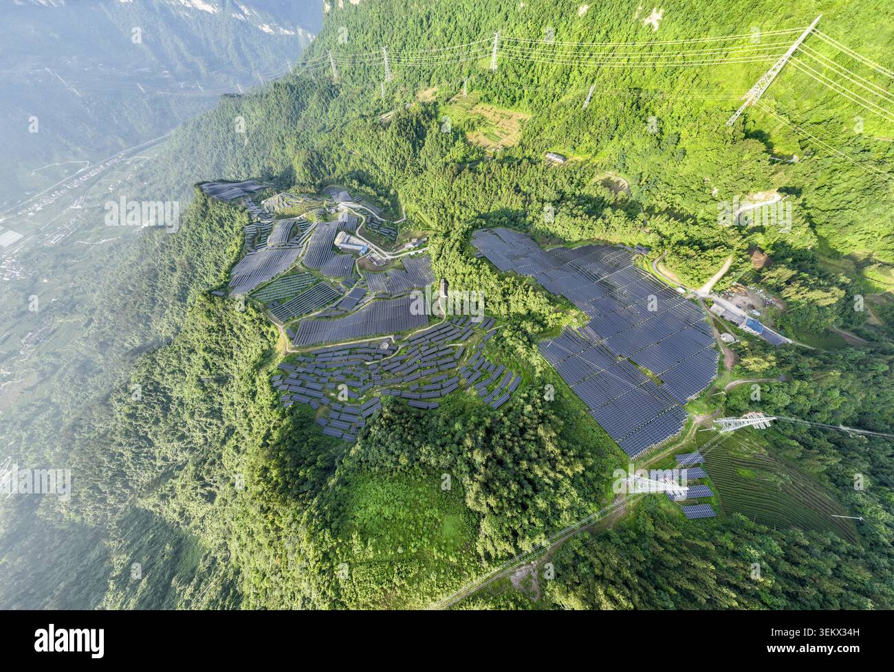 Solar panels stand against green mountains and blue sky at a ...