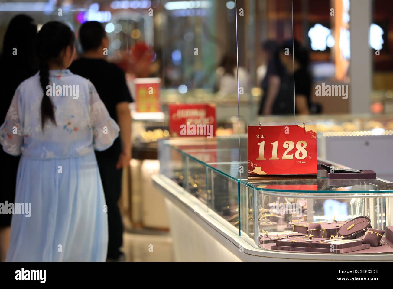 A consumer selects gold jewelry at a store in Huai'an, east China's ...