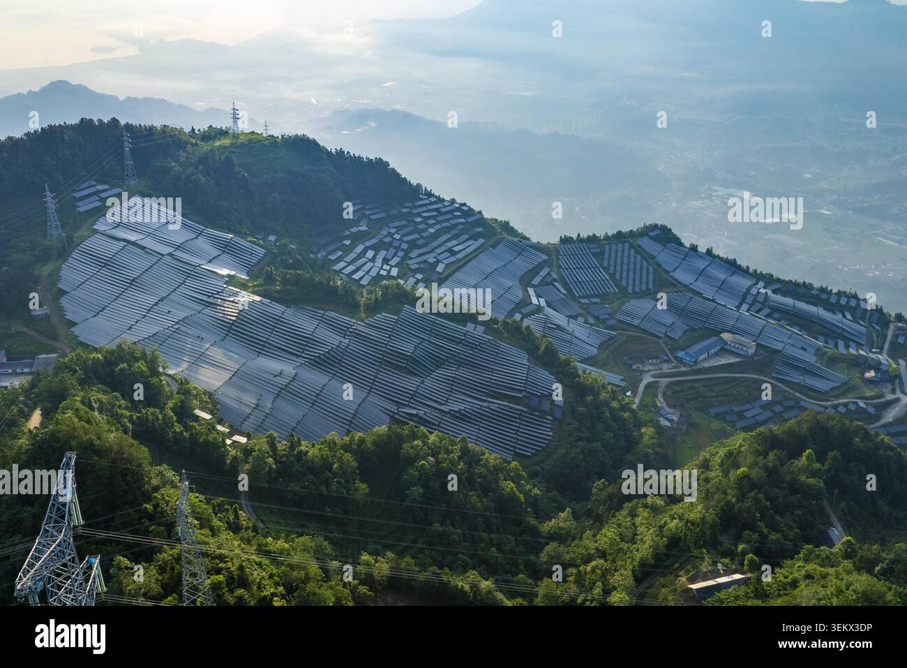 Solar panels stand against green mountains and blue sky at a ...