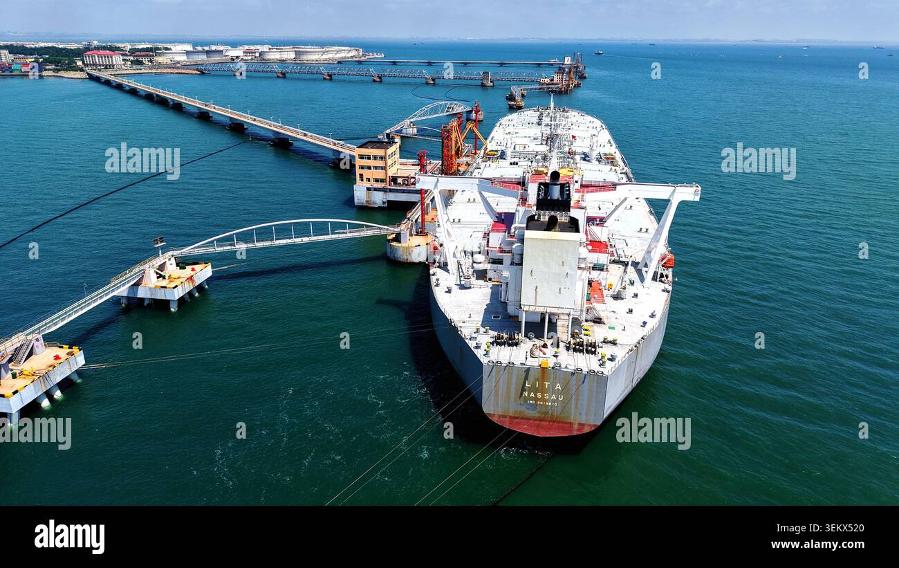 A crude tanker at a pier pumps oil to the storage facility on the shore ...
