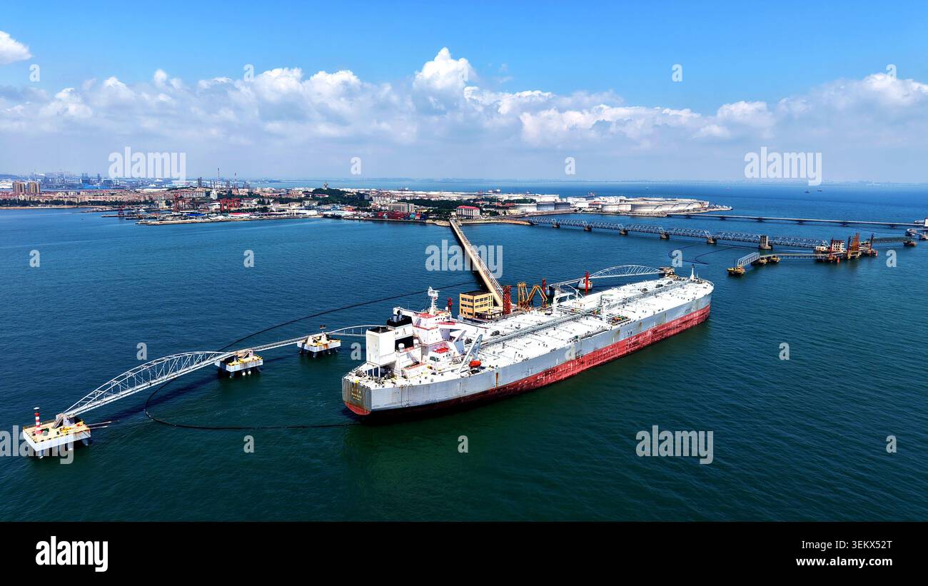 A crude tanker at a pier pumps oil to the storage facility on the shore ...
