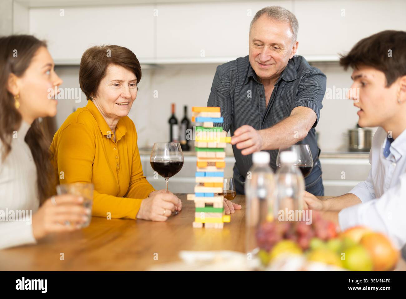 Enthusiastic parents and adult children play exciting game Jenga at ...