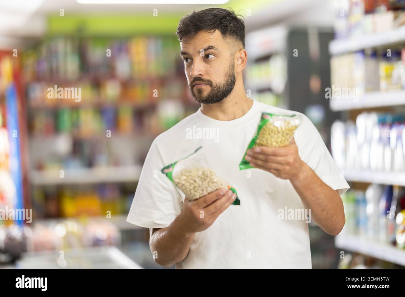 Supermarket shopping - man selects various nuts in produce section ...