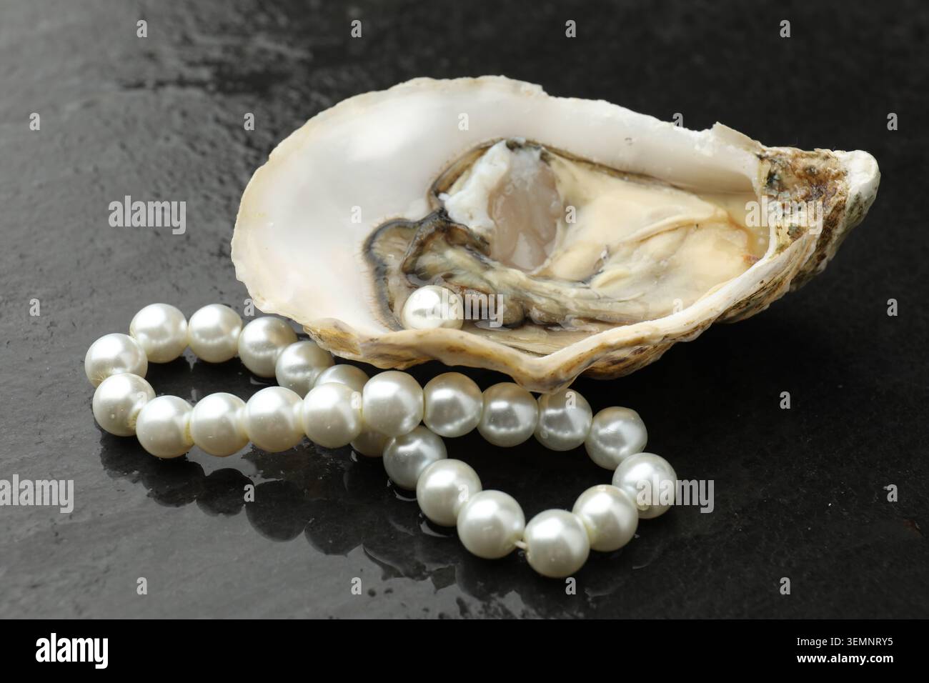 Oyster shell with pearls on black table, closeup Stock Photo - Alamy