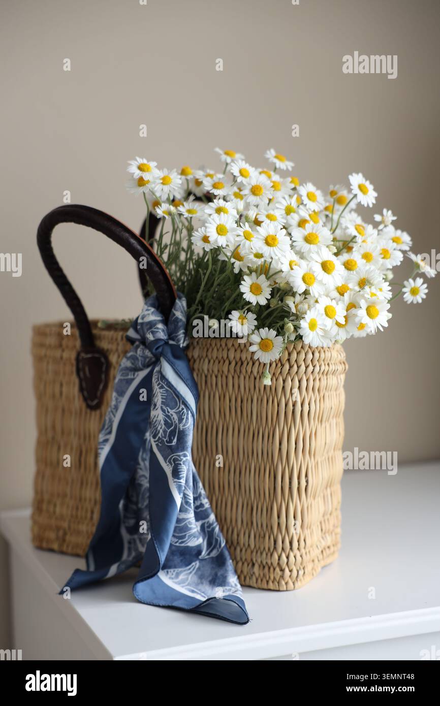 Beautiful chamomile flowers in bag on white table near light wall Stock ...