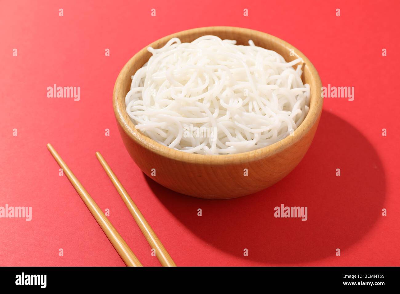 Tasty rice noodles in bowl and chopsticks on red table, closeup Stock ...