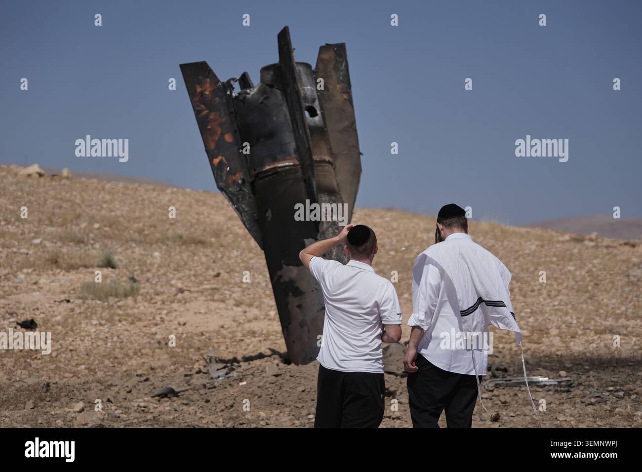 People inspect the wreckage of an Iranian missile that landed near the ...