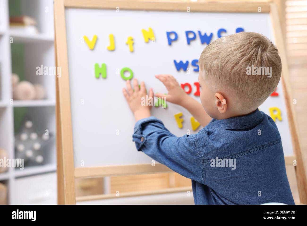Little boy learning alphabet with magnetic letters near whiteboard ...