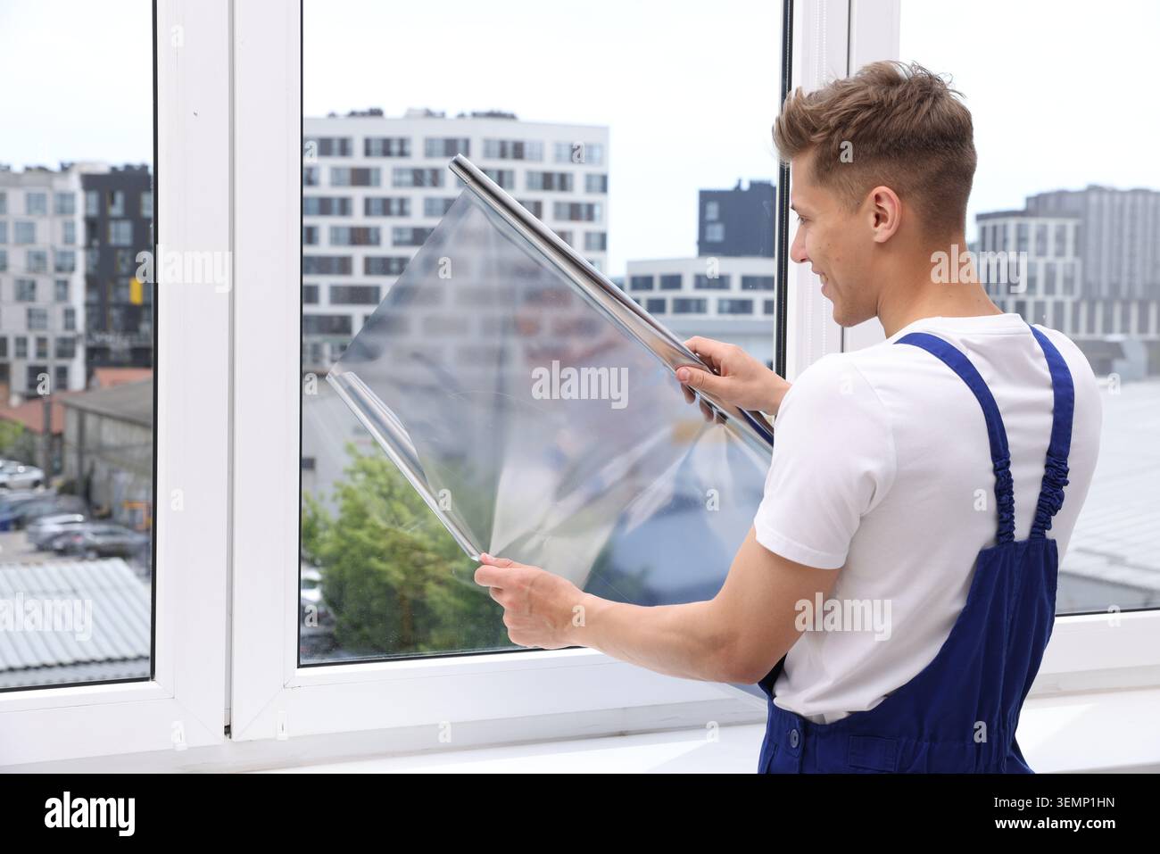 Professional worker tinting window with foil indoors Stock Photo - Alamy