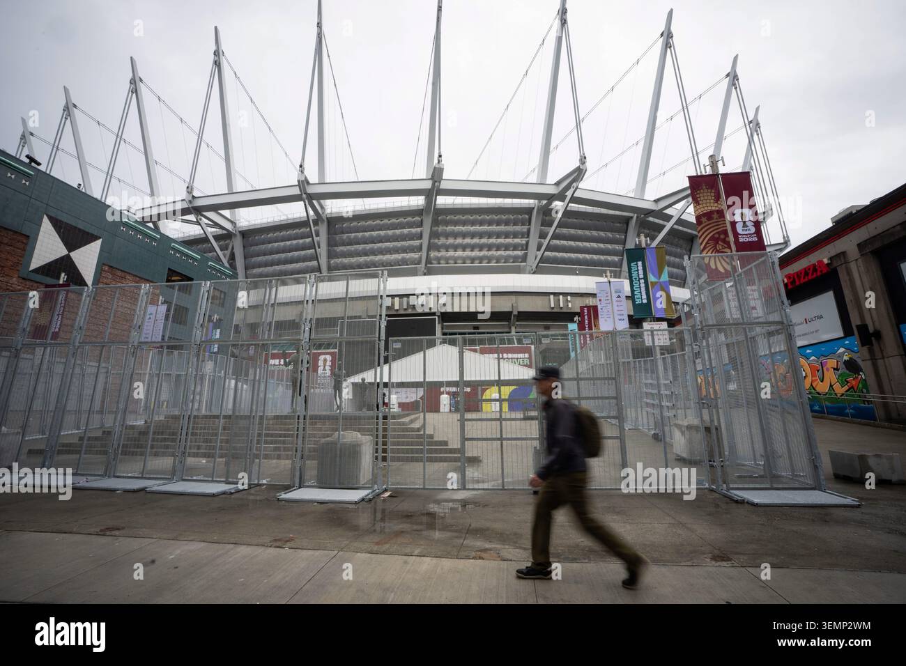 A man walks past fencing surrounding BC Place for the FIFA World Cup ...