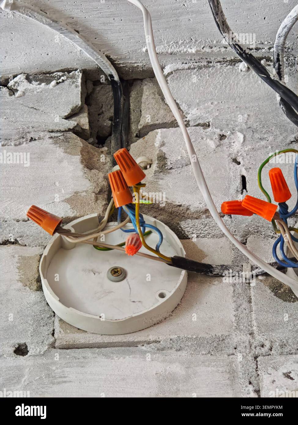 Workers install electrical wires and connectors inside a junction box ...