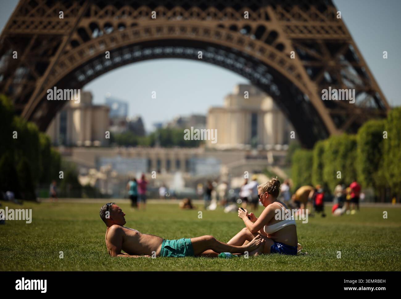 FILE - People enjoy the sun next to the Eiffel Tower in Paris, May 27 ...