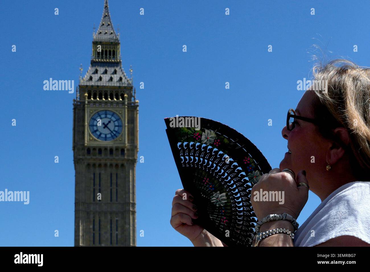 FILE - A woman cools herself outside the Palace of Westminster in ...