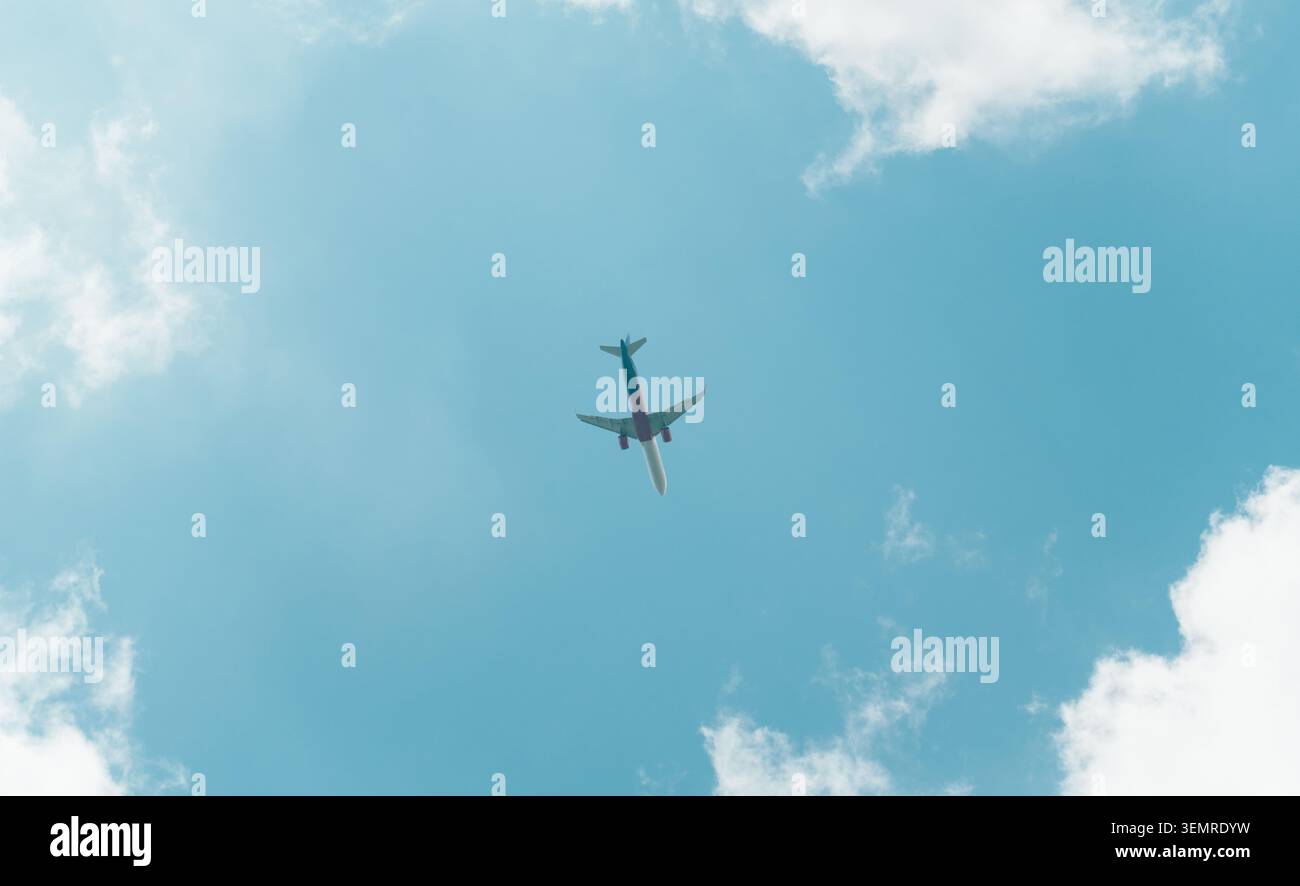 Commercial passenger airplane viewed from below against a blue sky with ...