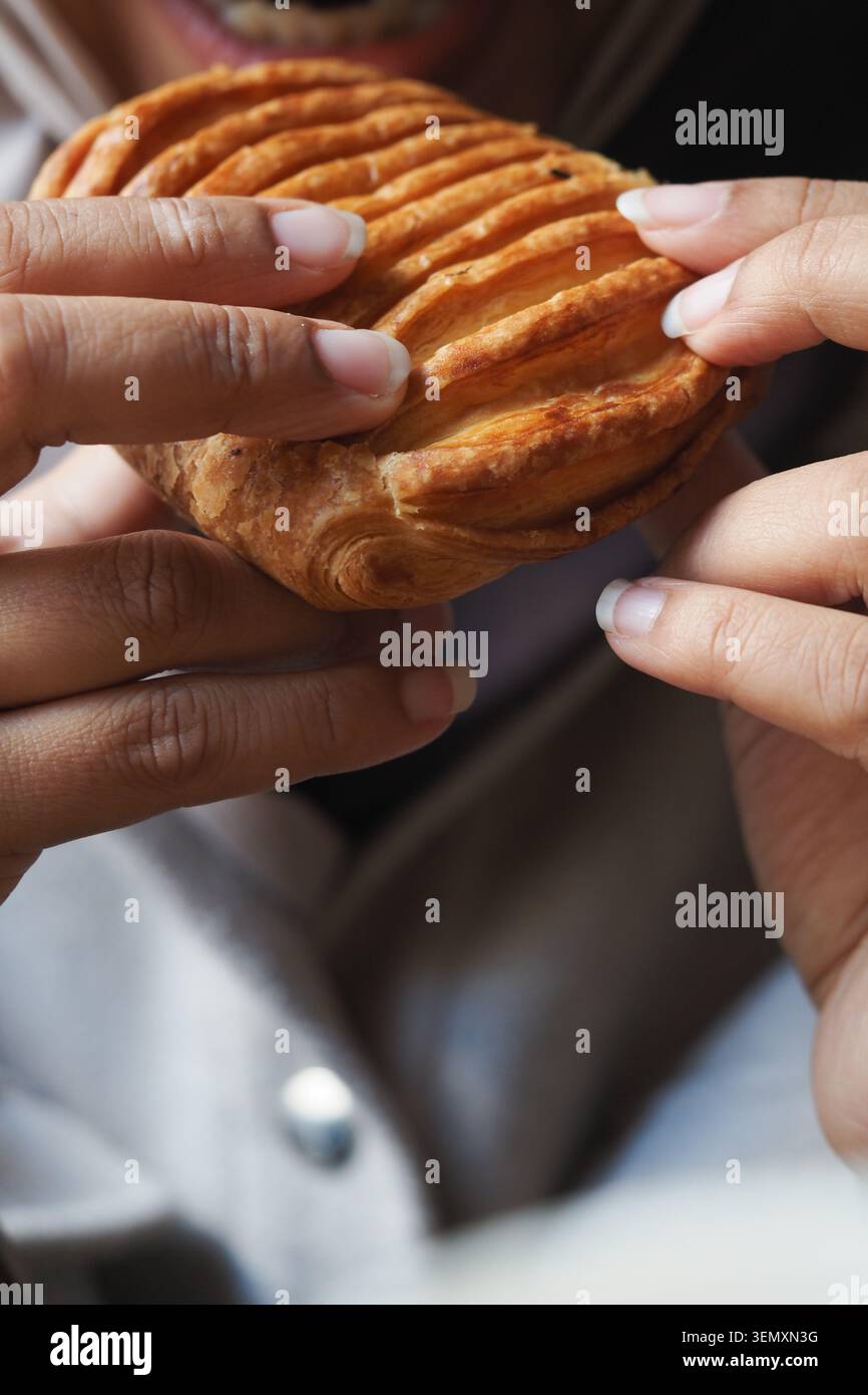 Person holds a baked pastry in hands while preparing to eat Stock Photo ...