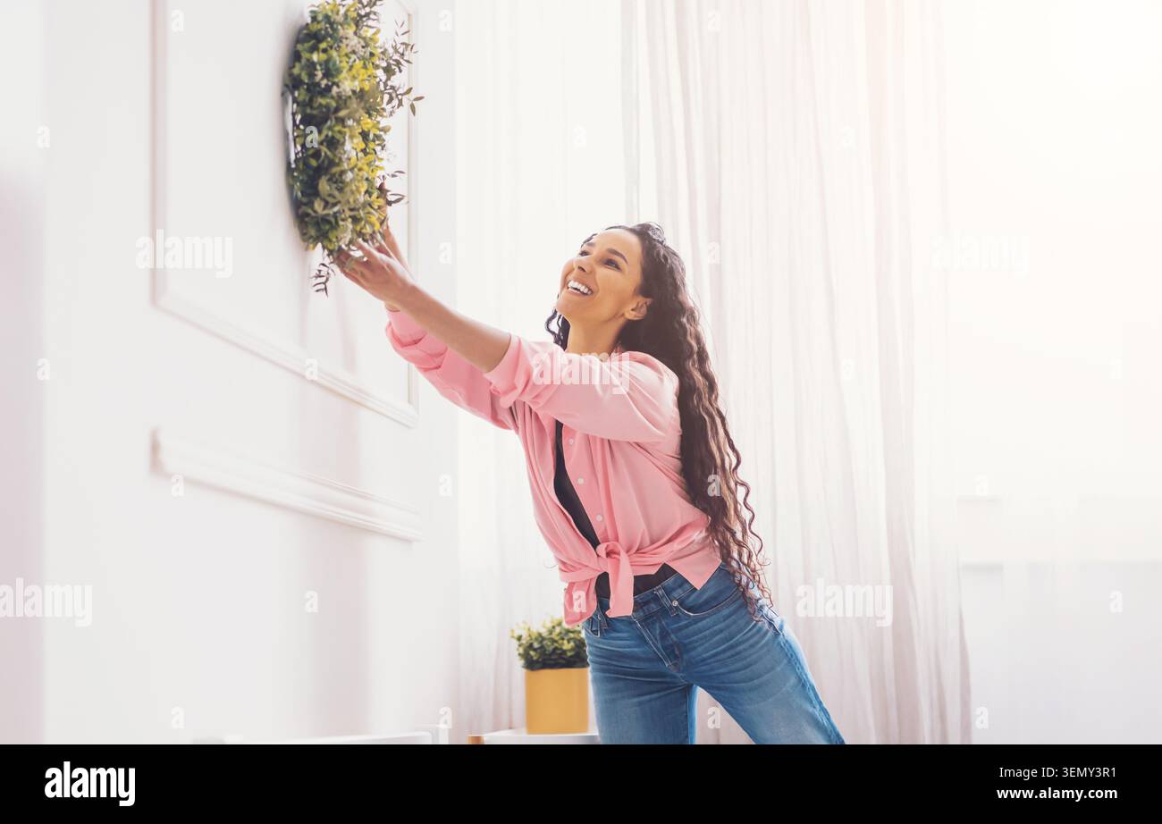 Smiling Young Woman Hanging Greenery On Wall At Home, Bright Lifestyle ...