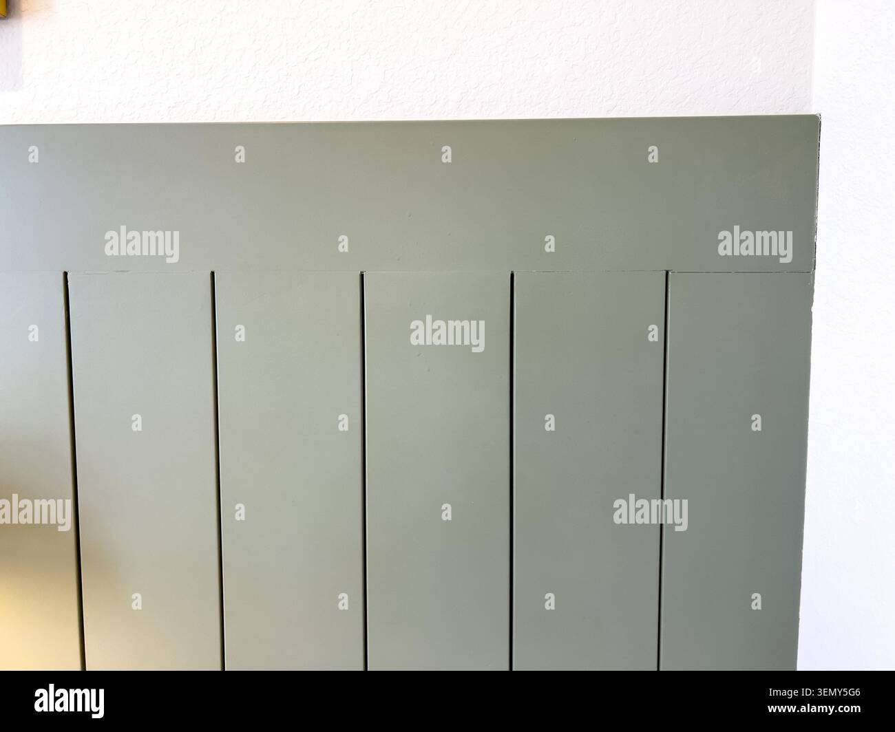 Close-up of vertical trim design on sage green wall paneling, styled in ...