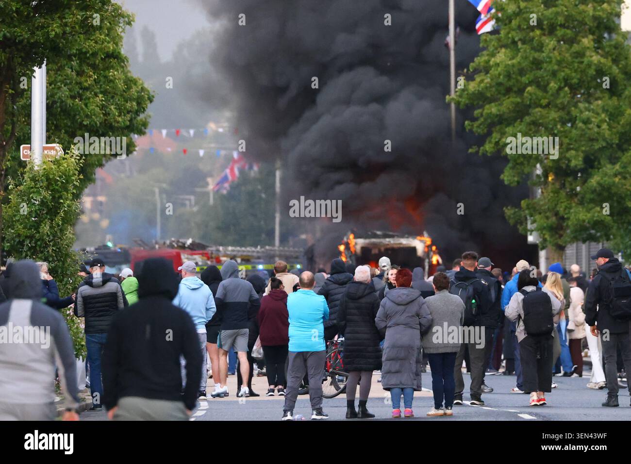People watch as a vehicle burns during a protest following a stabbing ...