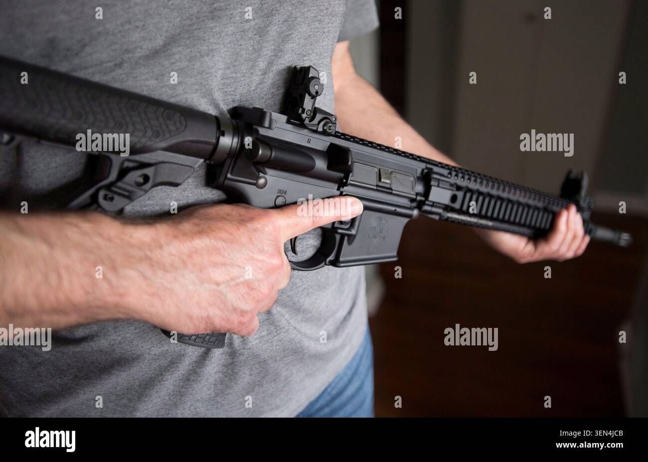 A restricted gun licence holder poses with an AR-15 at his home in ...
