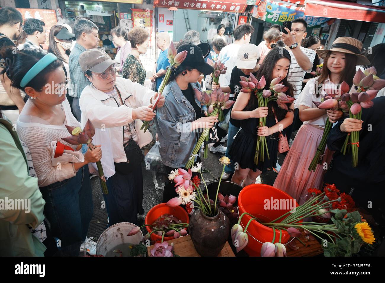 Visitors buy fresh lotus flowers at a morning market in Hangzhou, east ...
