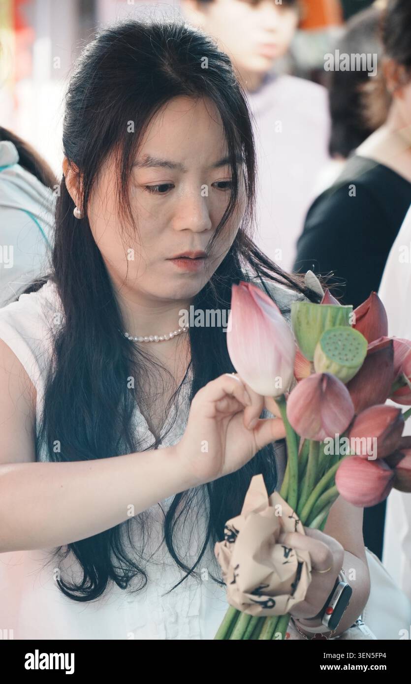 Visitors buy fresh lotus flowers at a morning market in Hangzhou, east ...