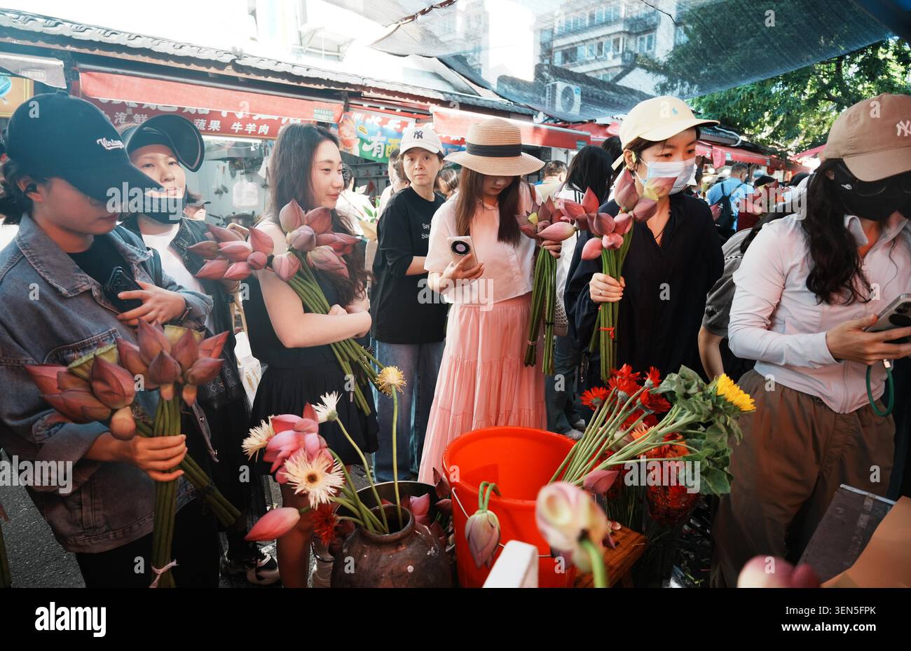 Visitors buy fresh lotus flowers at a morning market in Hangzhou, east ...