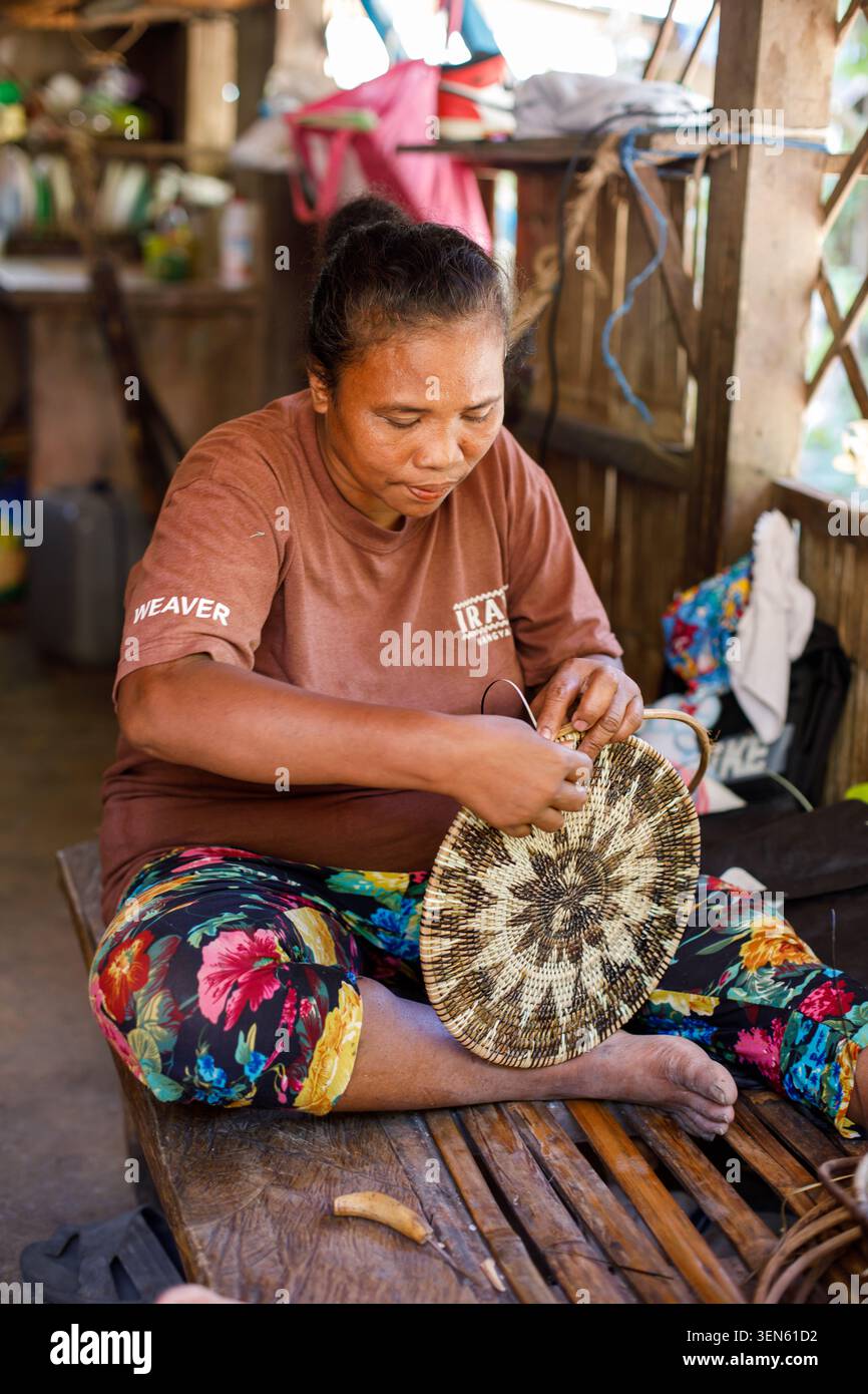 A Mangyan artisan weaves a traditional basket by hand in a village ...