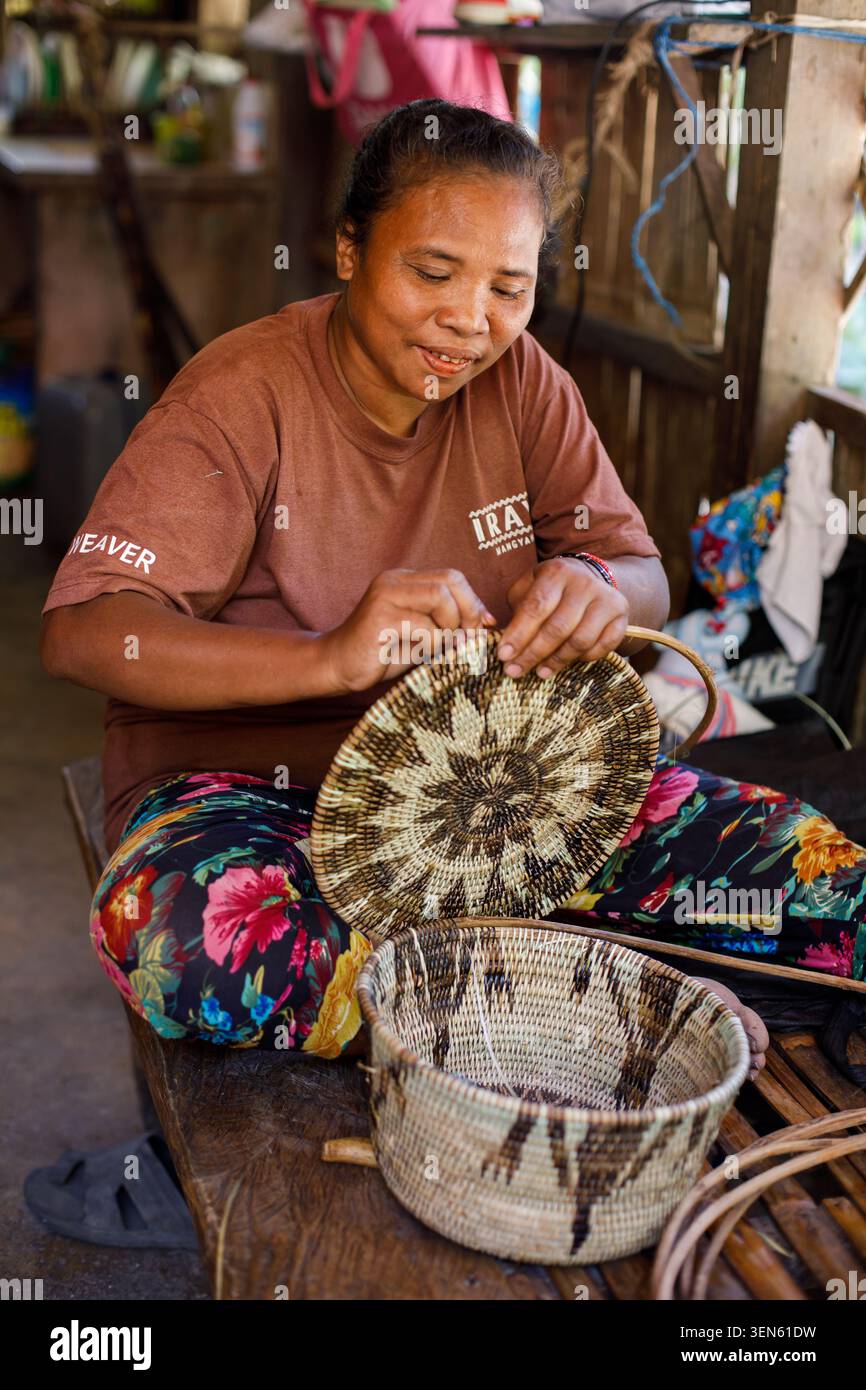 A Mangyan artisan weaves a traditional basket by hand in a village ...