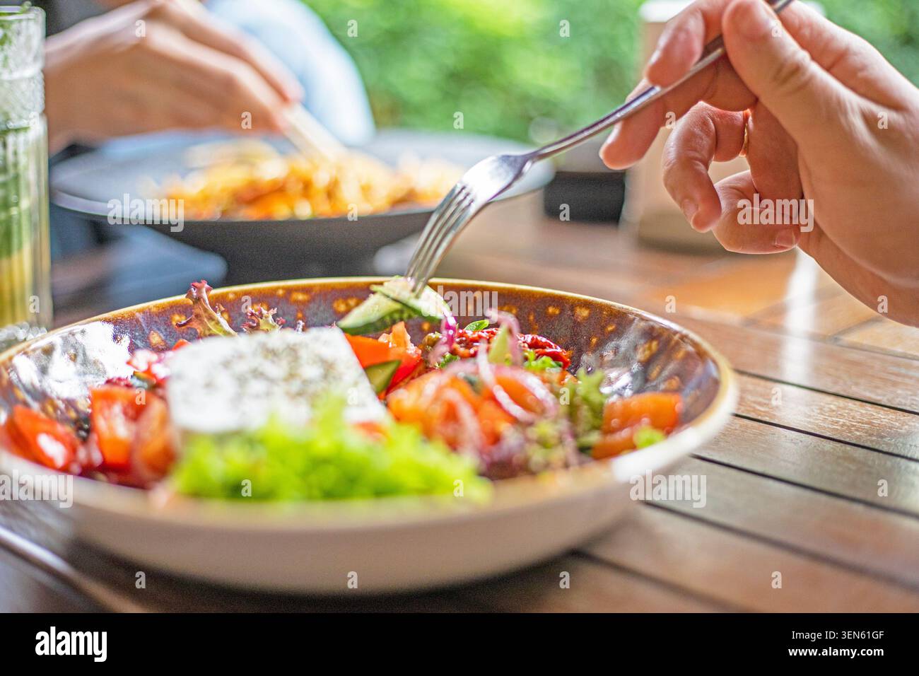 eating a Greek salad with feta cheese and pieces of dried rye bread ...