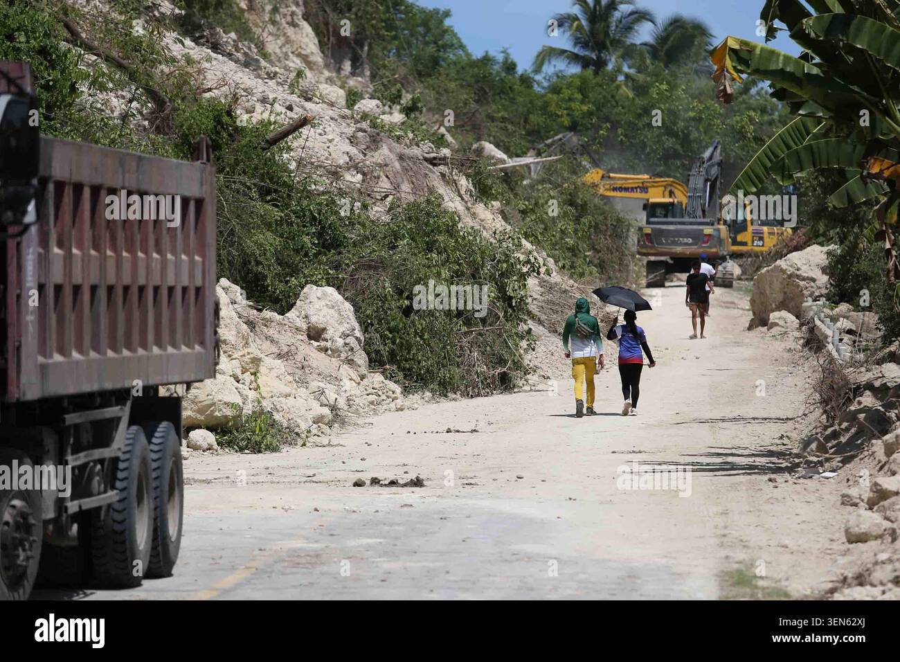 People walk past a landslide following an earthquake in Sarangani ...