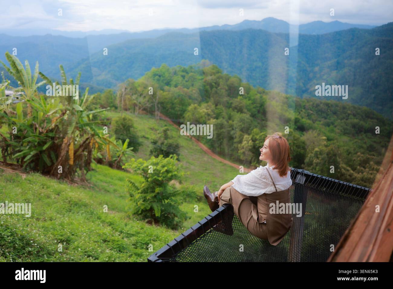Happy woman tourist enjoys travel adventure, sitting on balcony net ...