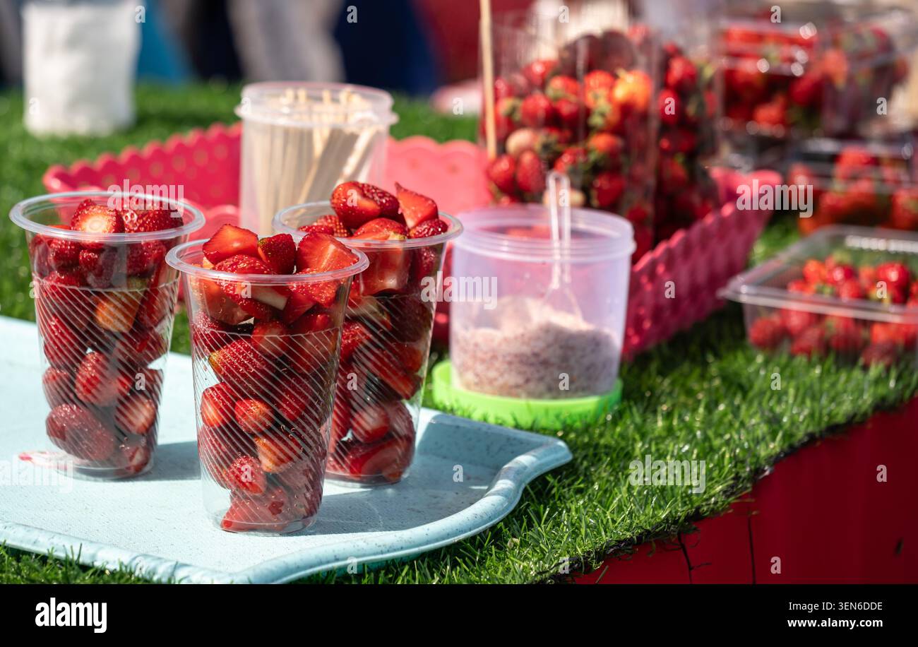 Sliced fresh strawberries in plastic cups with dipping seasoning served ...