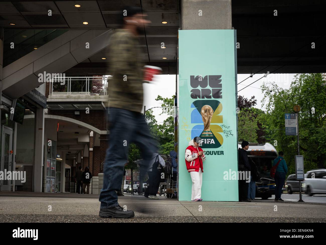 A person waits on their phone on a pillar decorated with FIFA World Cup ...
