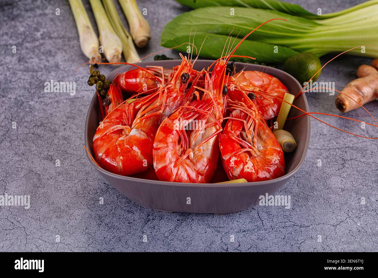 Bowl of cooked red shrimps with fresh ingredients like lemongrass, bok ...