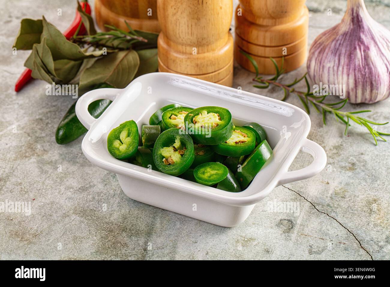 Close-up of sliced green jalapeno peppers in white rectangular dish ...