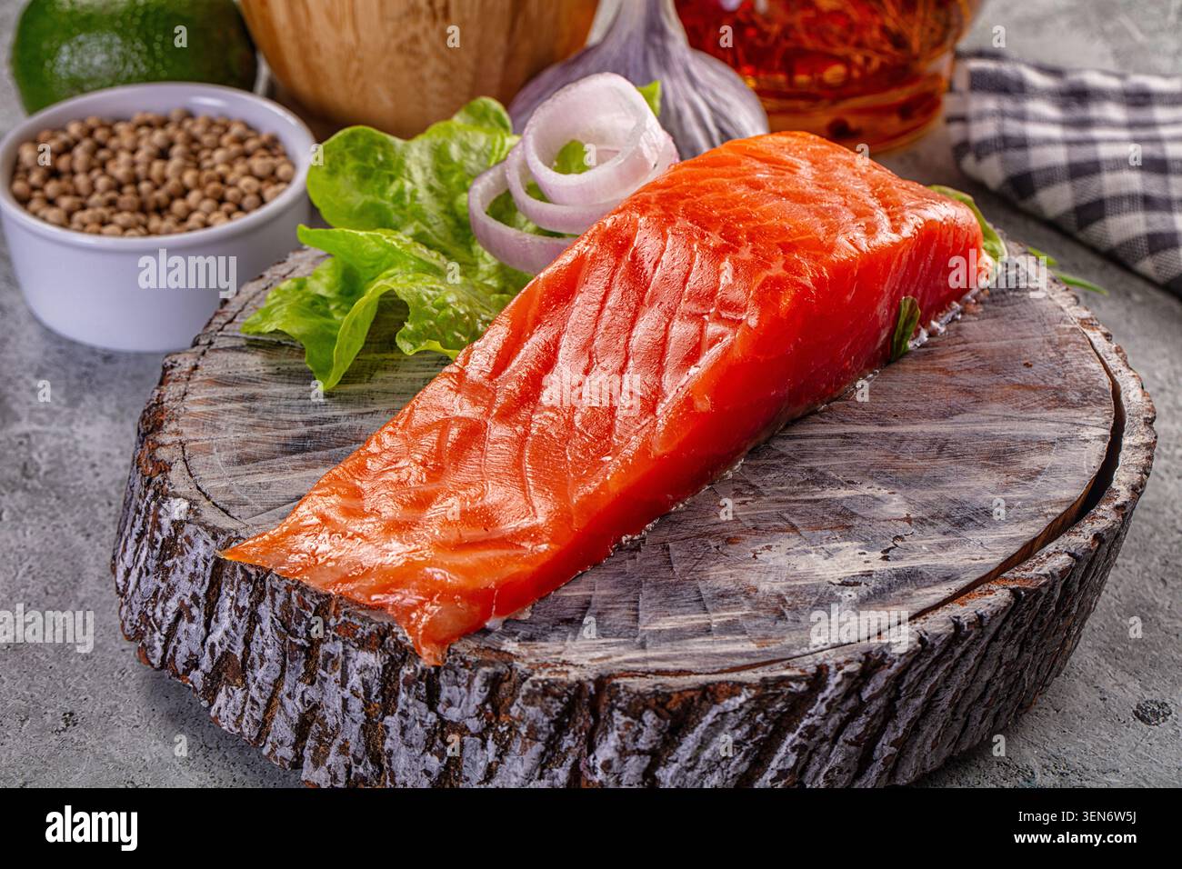 Vibrant raw salmon fillet on rustic wooden board, surrounded by fresh ...