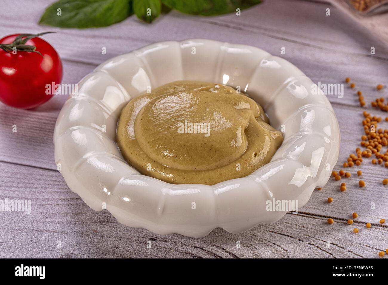 Creamy yellow mustard sauce in decorative white ceramic bowl ...