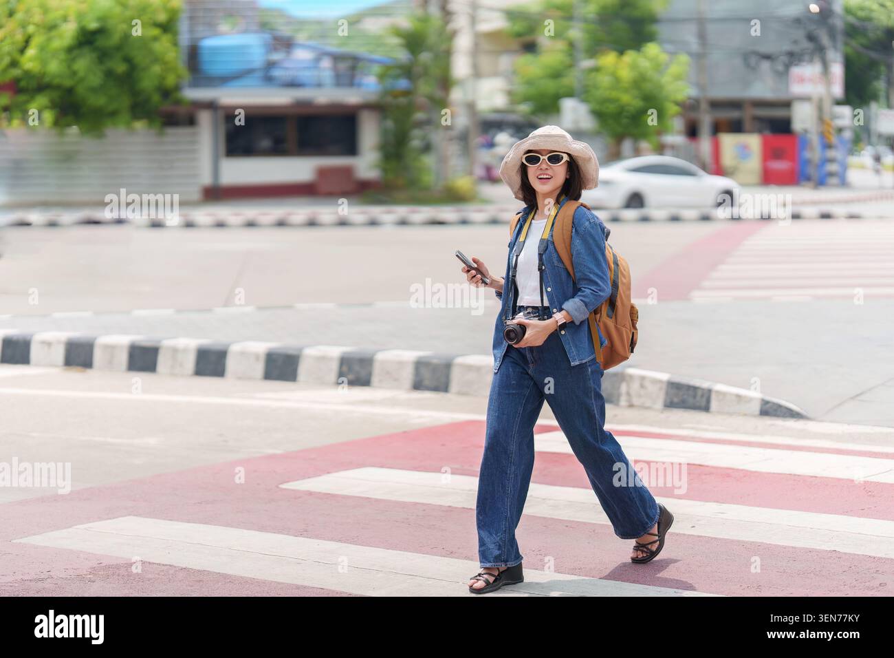 Happy Asian woman tourist walking on crosswalk with camera and phone ...